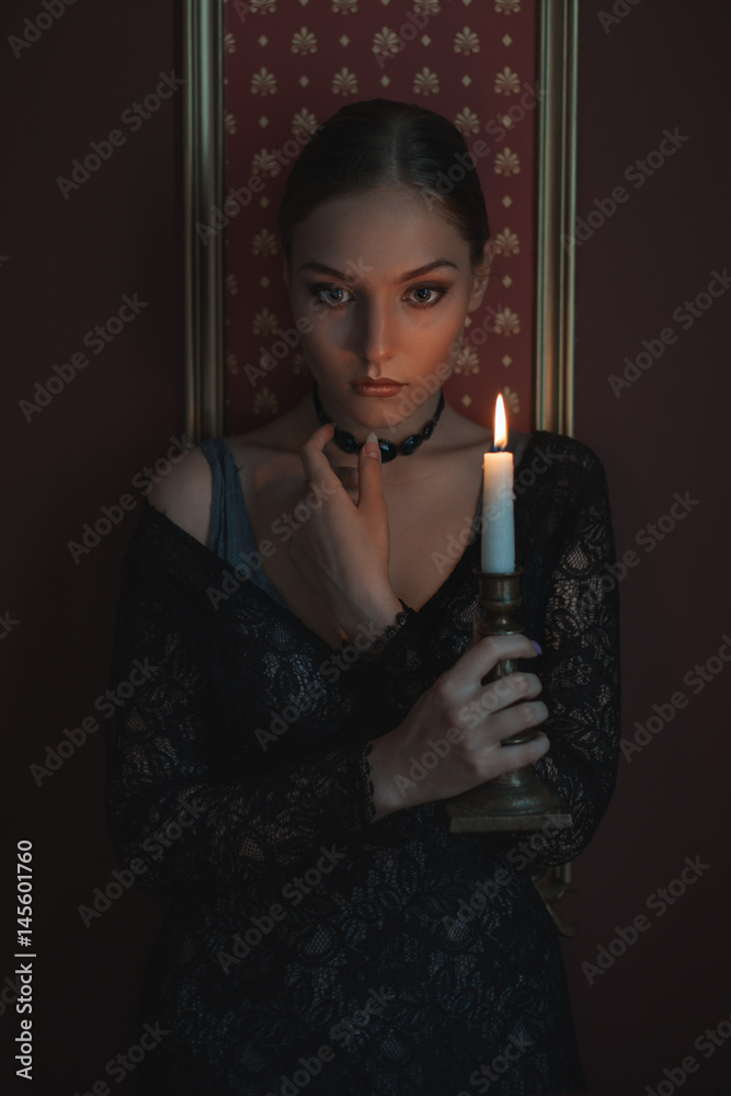 Beautiful and sad woman in a dark room with a candle. Stock Photo ...