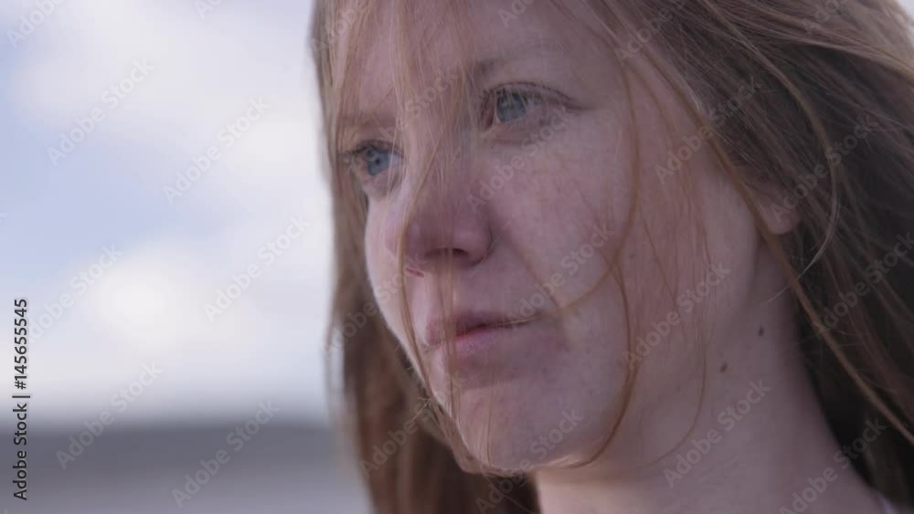 woman staring out into distance while wind blows here hair Stock Video ...