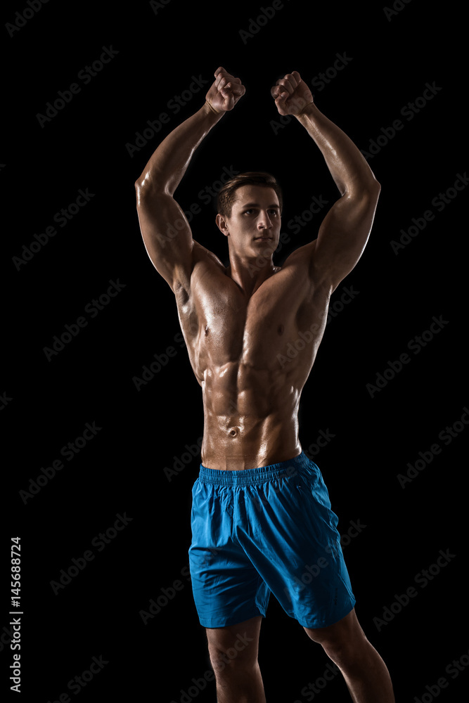 Muscular and fit young bodybuilder fitness male model posing over black ...