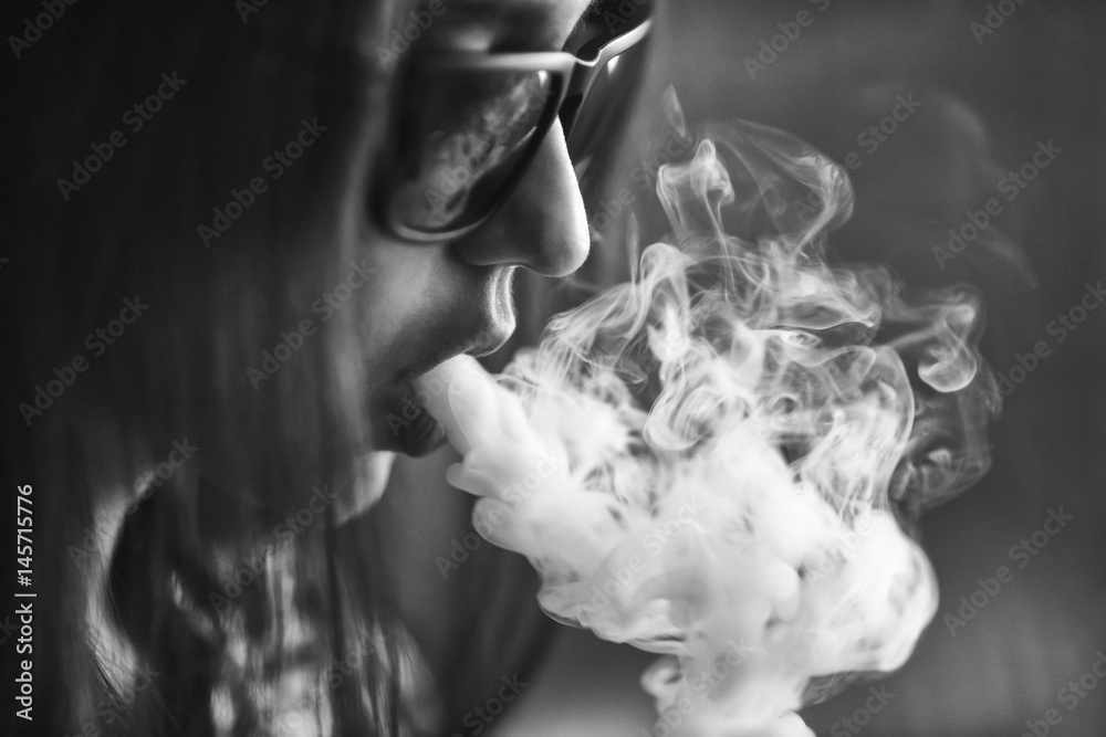 Vape. Young handsome white girl in sunglasses is admiting puffs of ...