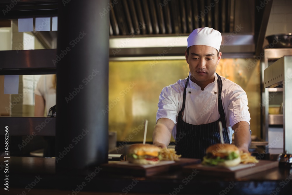 Chef placing tray with French fries and burger at order station Stock ...