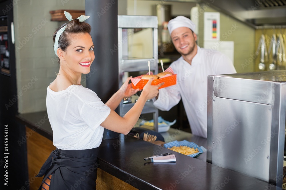 Chef giving burgers to waitress in commercial kitchen Stock Photo ...
