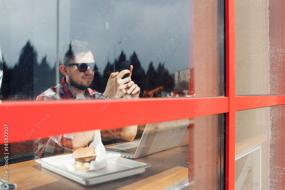 Eating at work place - fast food. burger near laptop. lunch break while ...