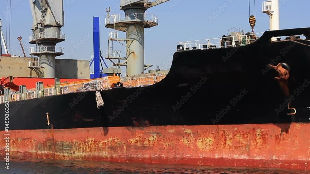 Close-up pan shot of cargo freight ship berthed in commercial sea port ...