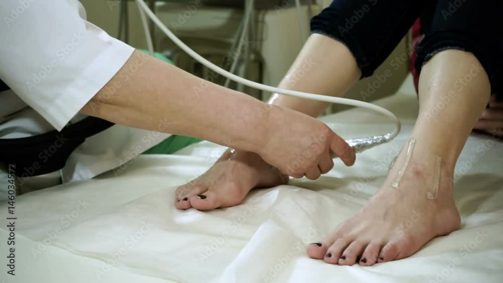 Female doctor examining the woman's right foot using an ultrasound ...