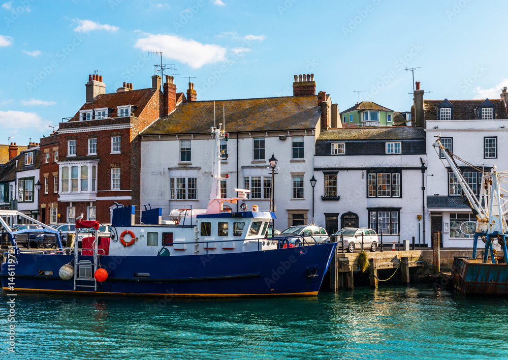 Boats anchored in a small harbor, in the background stone buildings and ...