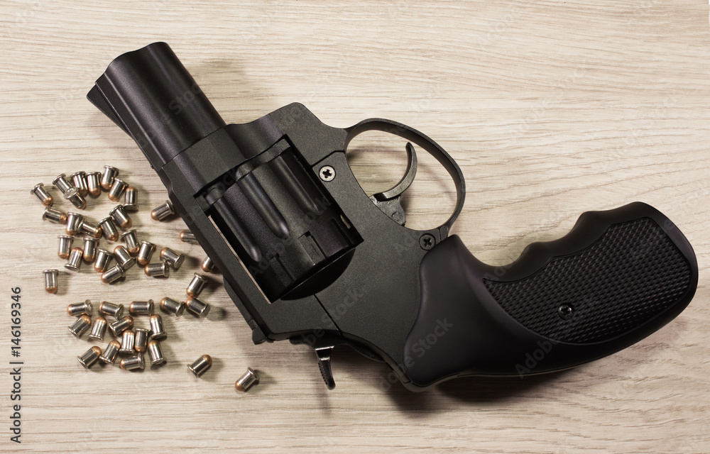 Black metal Flaubert revolver with bullets laying on a bright wooden ...
