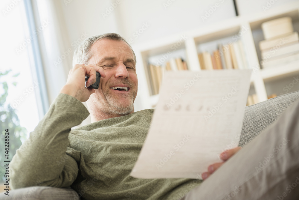 Older Caucasian man talking on telephone reading paperwork Stock Photo ...