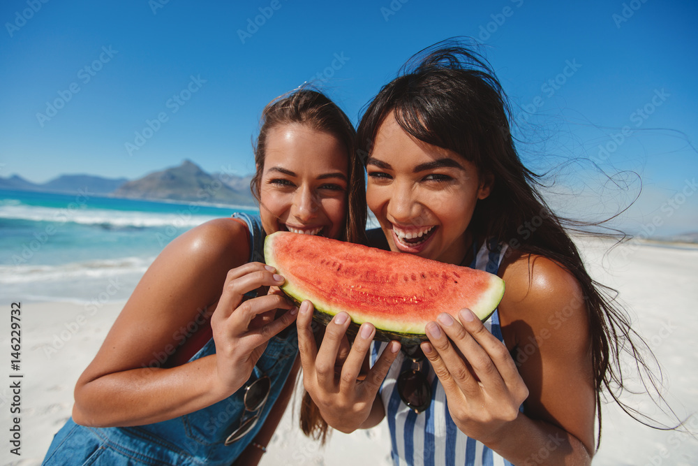 Female friends on beach having a slice of watermelon Stock Photo ...