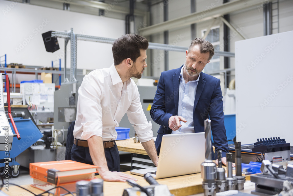 Two men at table in factory shop floor with laptop Stock-Foto | Adobe Stock