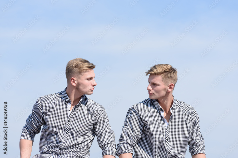 handsome twins posing with serious faces on sky background Stock Photo ...