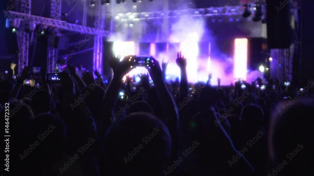 Happy audience jumping and raising their hands to air at rock group ...