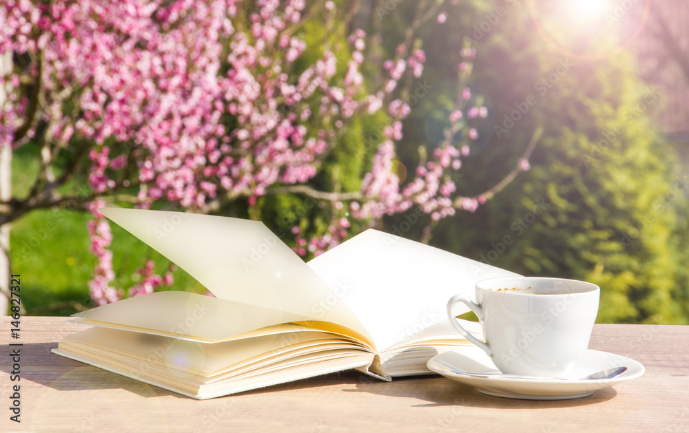 Coffee cup with open book over spring garden Stock Photo | Adobe Stock