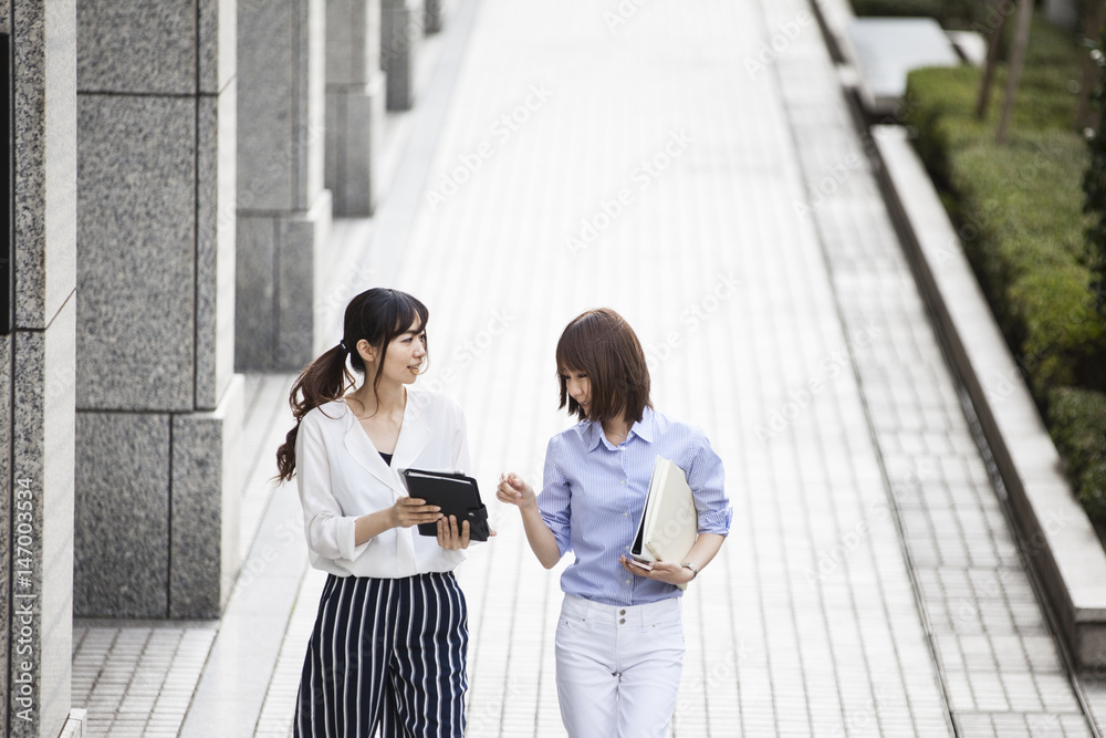 Two business women walking while talking happily Stock Photo | Adobe Stock