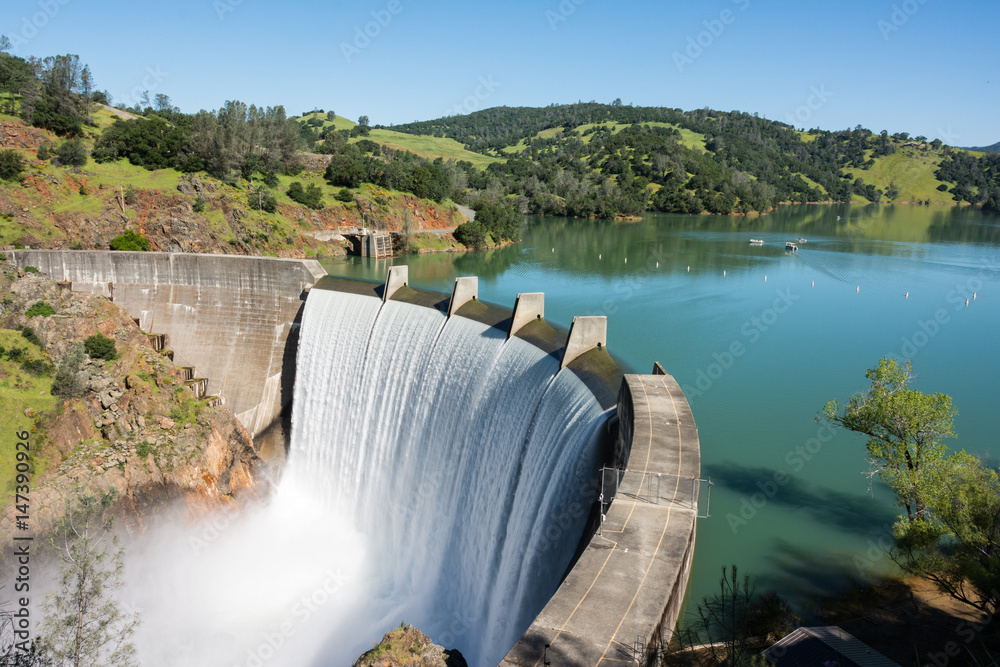 Water spills over the top of Englebright Dam on the Yuba River. A ...