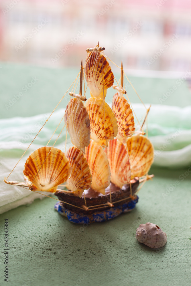 small ship model made of shells on the emerald background of the next ...