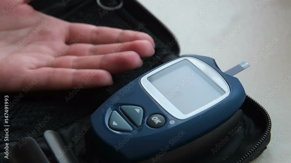Close-up shot of woman pricking finger with lancing device and taking ...