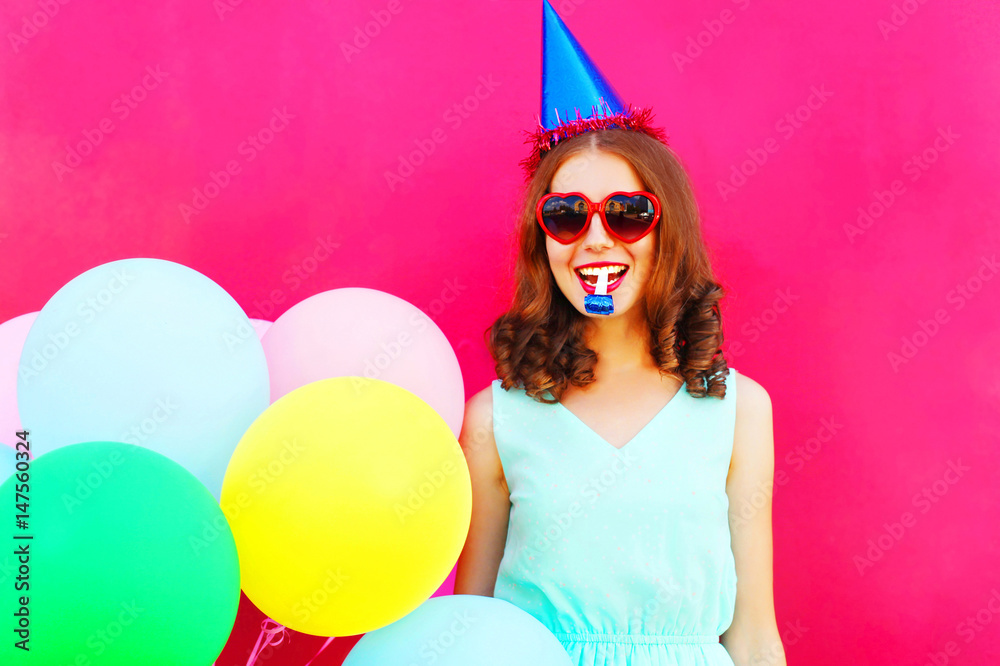 Happy woman in a birthday cap with an air colorful balloons over a pink ...