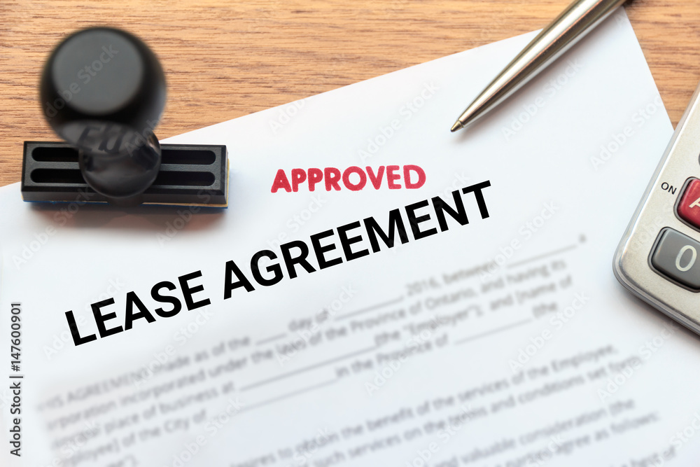 Approved lease agreement document with rubber stamp and calculator on ...