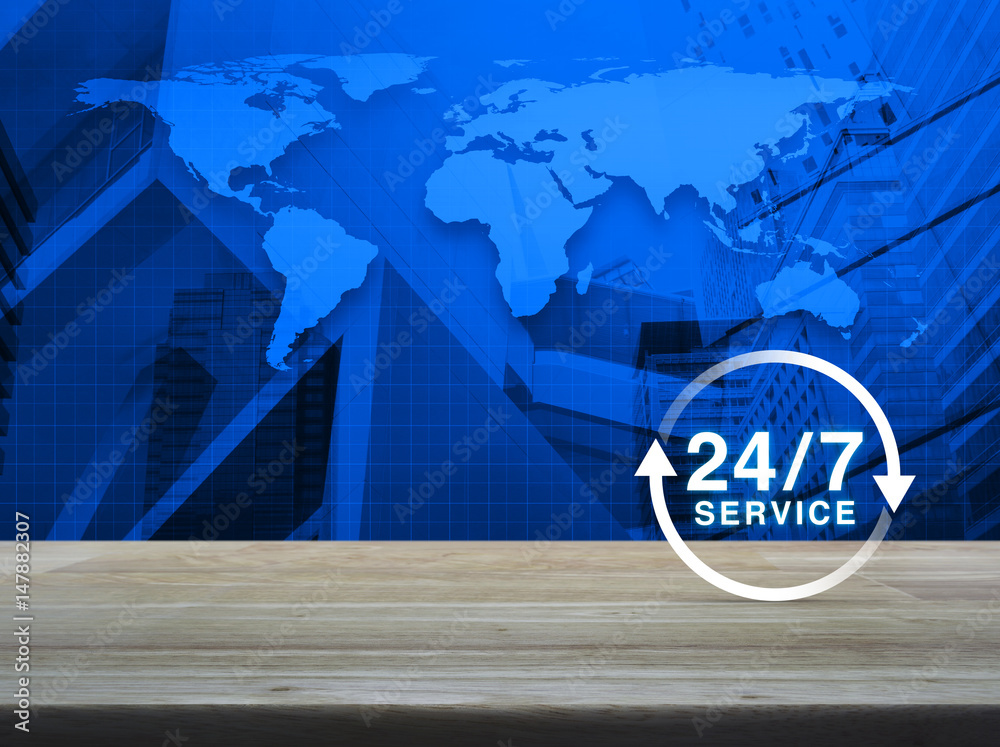 24 hours service icon on wooden table over world map and city tower ...
