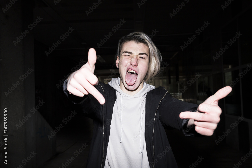 Young man sticking out tongue and giving the finger Stock Photo | Adobe ...