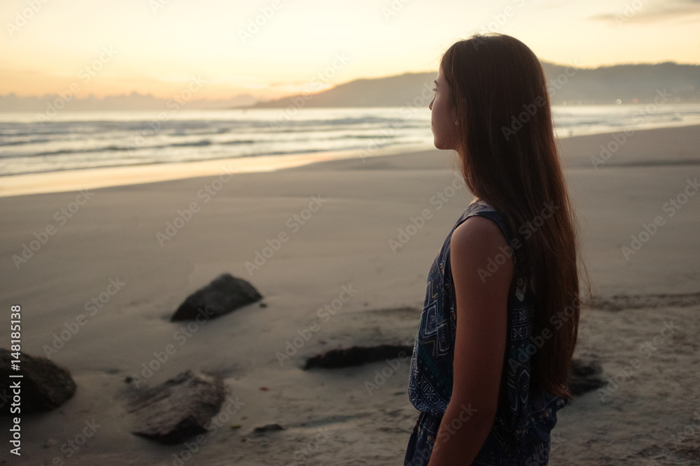 Young woman looking into the ocean and sunset or sunrise, summer on the ...