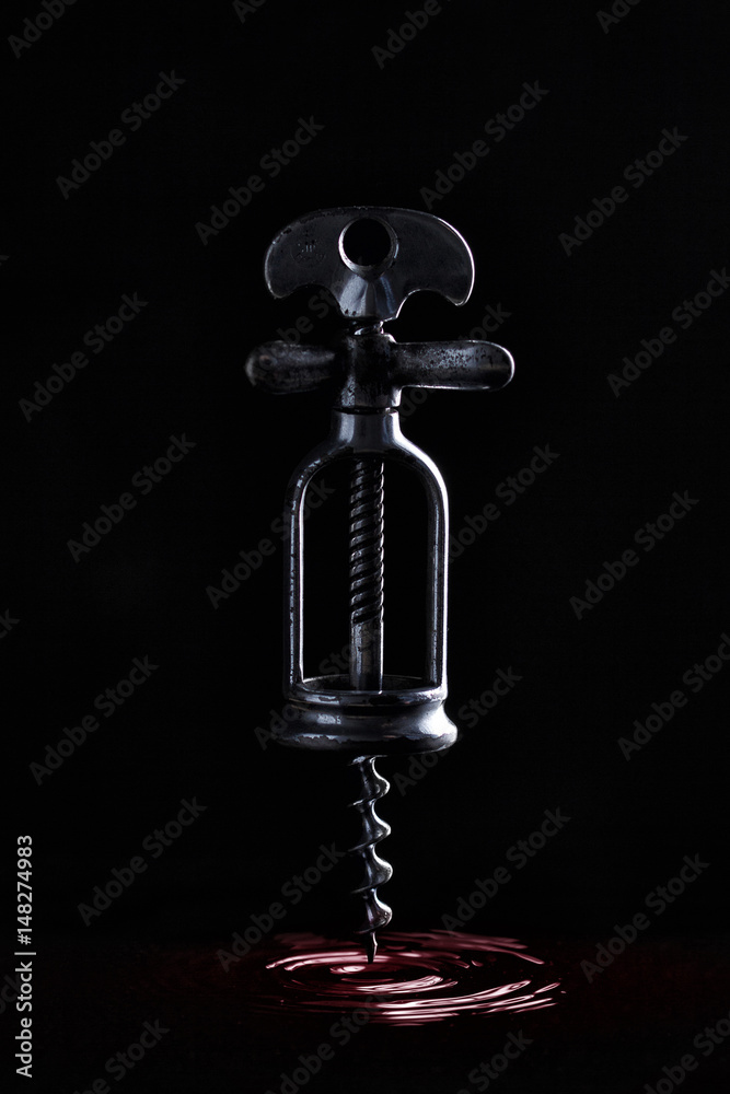 Antique corkscrew hanging in the air on a black background. An ancient ...