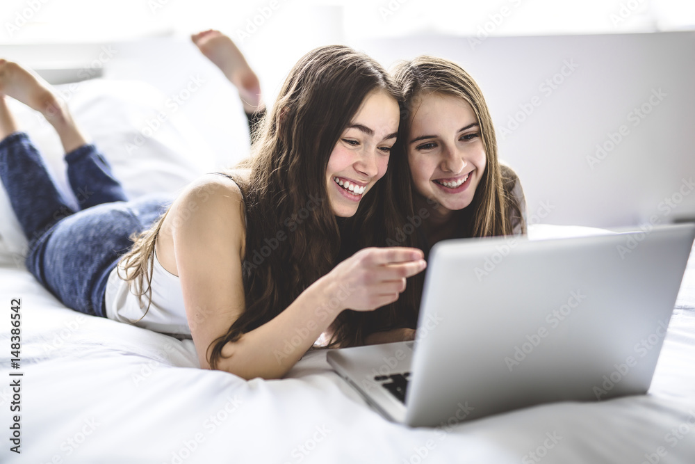Teen Girls Lying On Bed Using A Laptop Stock Photo | Adobe Stock