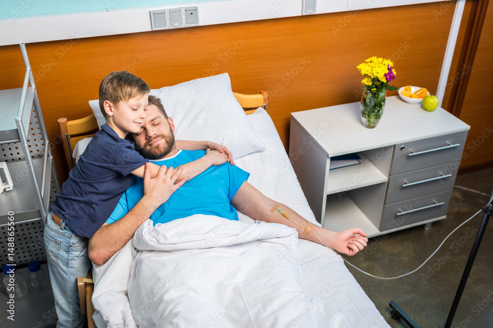 father with son embracing while laying on hospital bed at ward, dad and ...
