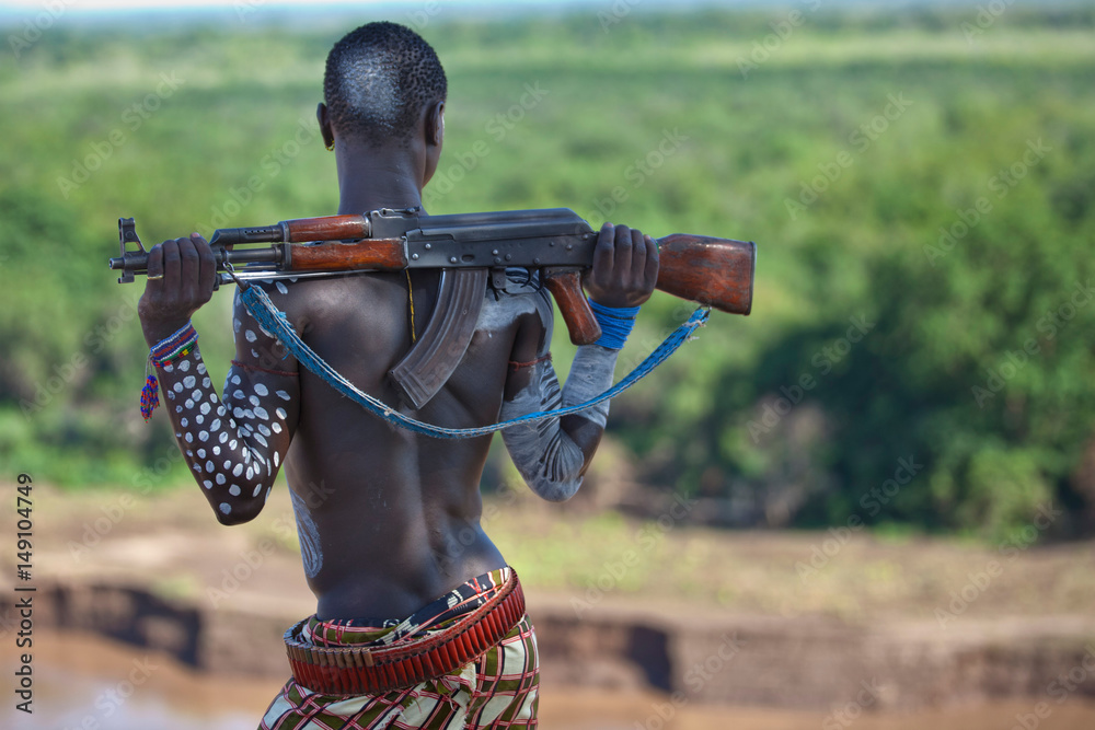 Kara Tribe man with rifle looking across the Omo River, Ethiopia Stock ...