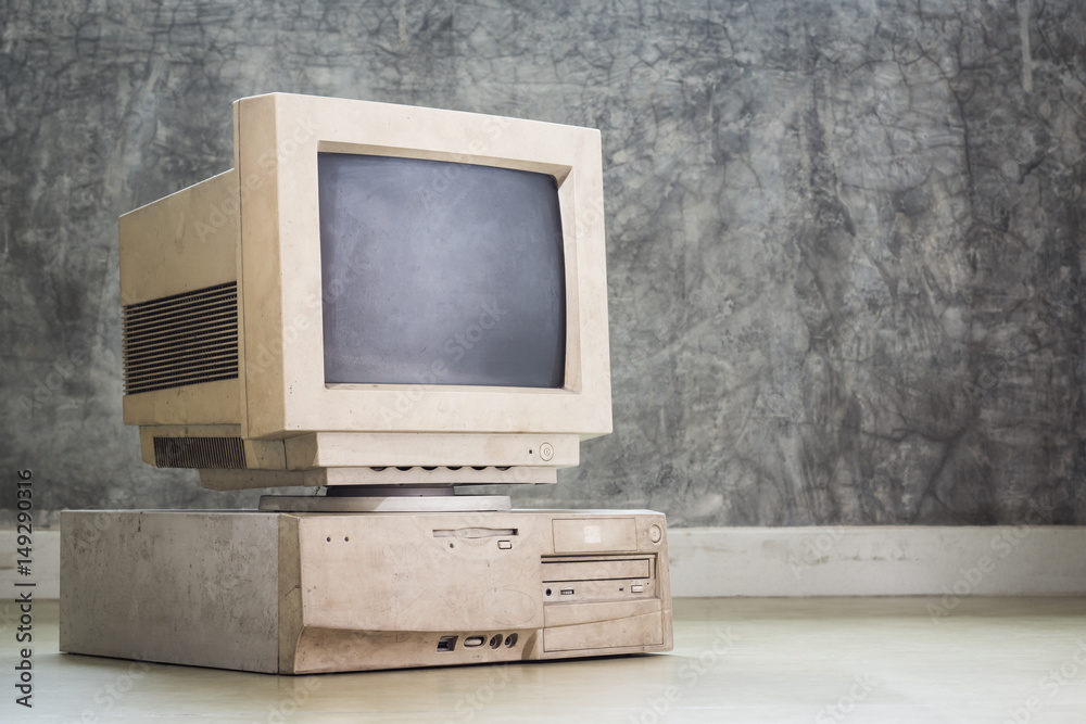 old and obsolete computer set on the floor with grunge concrete wall ...
