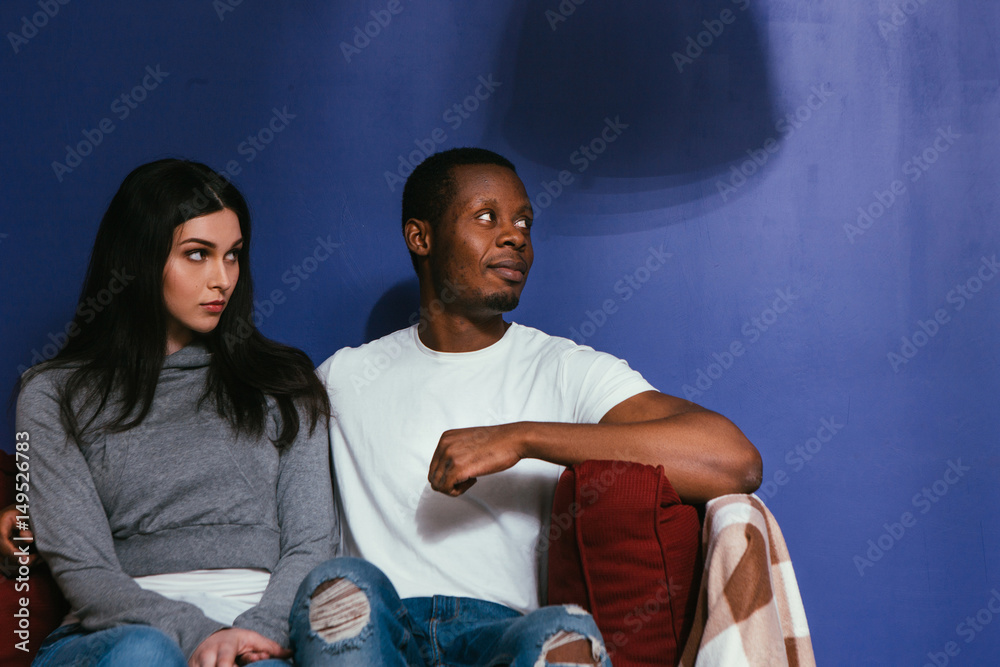 Young international couple of white woman and black man sit on couch at ...