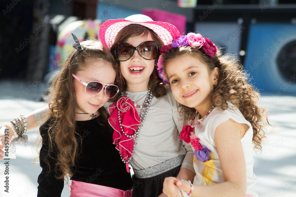 three cheerful little girls of the girlfriend walking with shopping ...