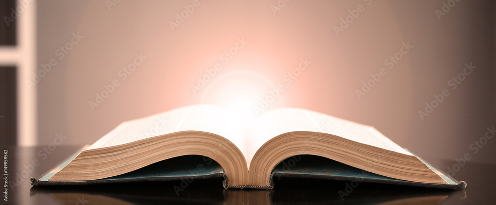 Image of an open book with a beautiful yellow light on a black ...