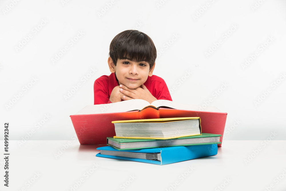 indian cute little boy or kid reading book over study table, isolated ...