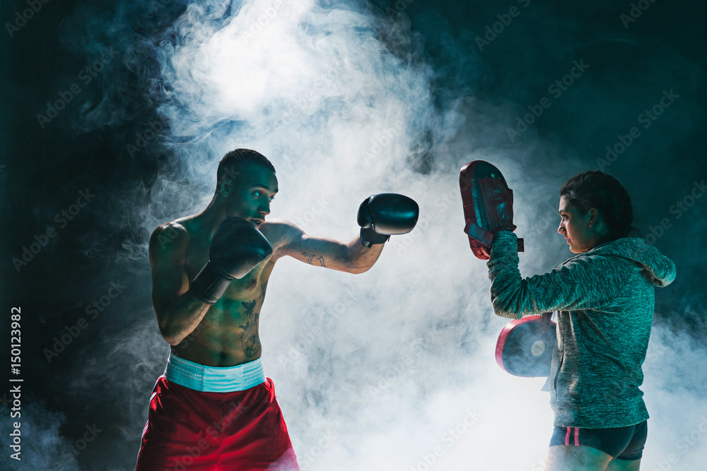 Handsome Afro American boxer with bare torso is practicing punches with ...