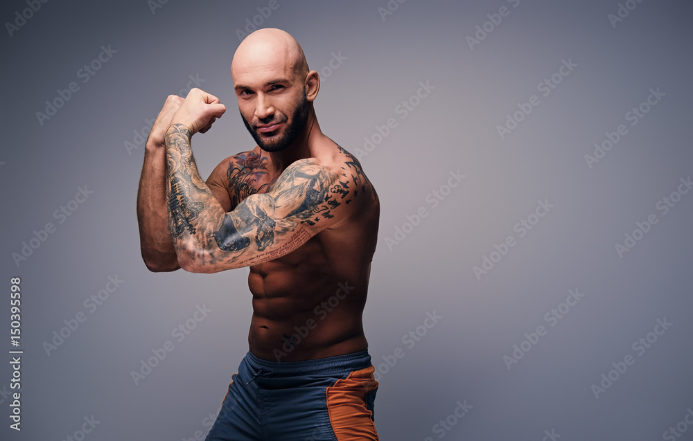 handsome muscular shaved head male with tattooed torso shows his ...