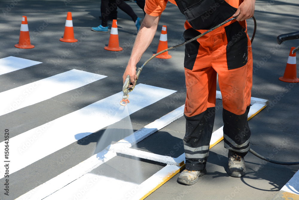 Worker is painting a pedestrian crosswalk. Technical road man worker ...