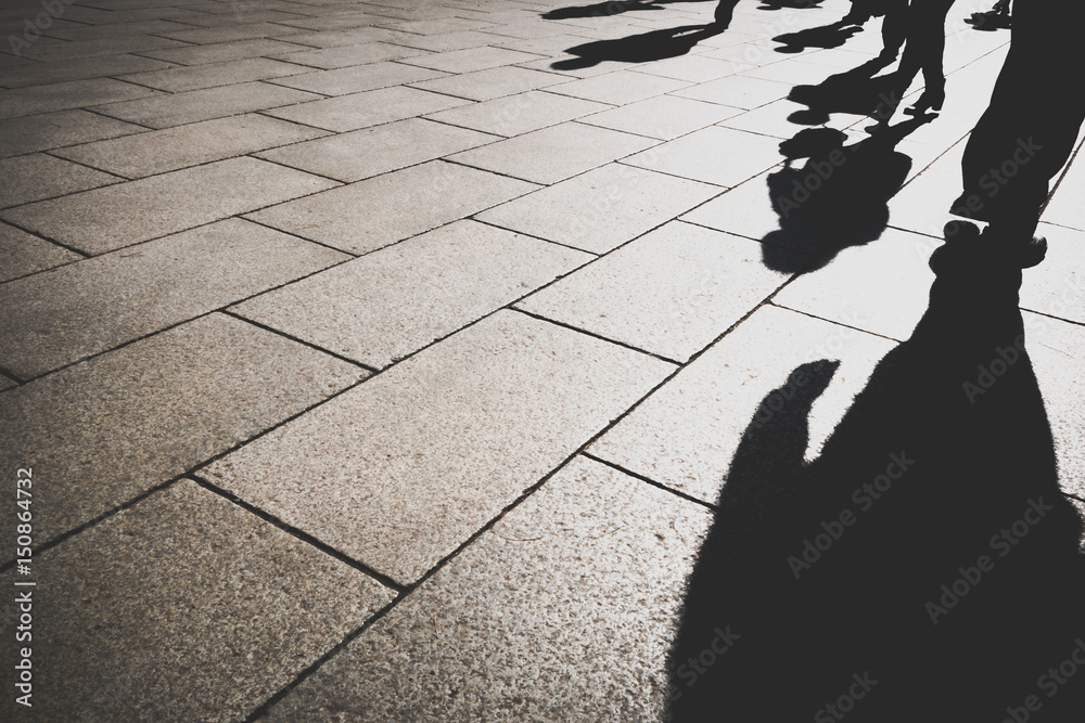 shadow of people in day light on pattern granite city street, copy ...