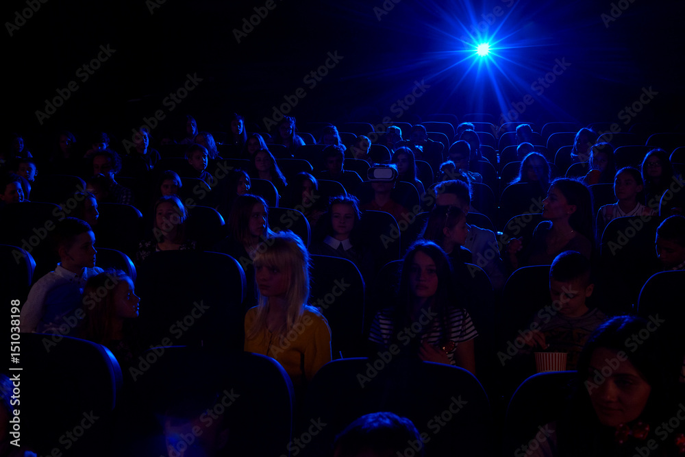 Shot of a dark cinema auditorium full of kids watching a movie together ...