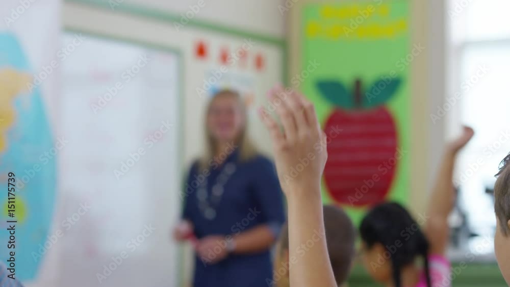 Teacher gives lesson in school classroom and students raise hands, rack ...