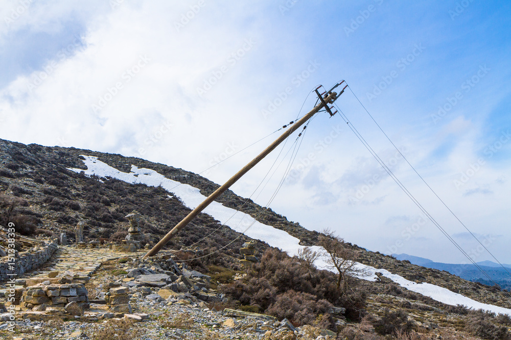 Leaning power pole with electric power lines on high mountain grLeaning ...