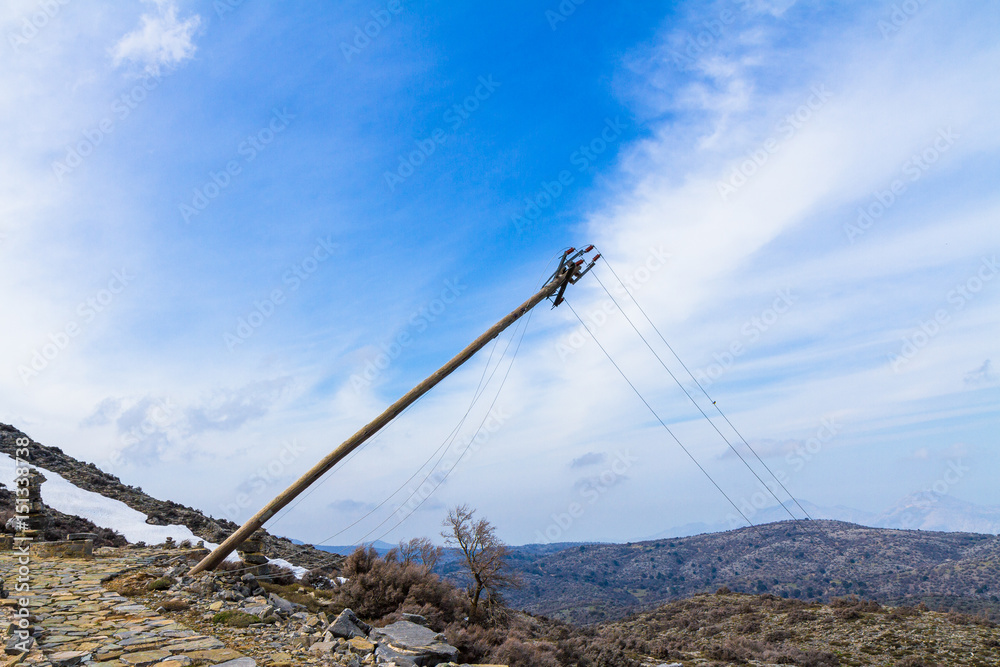 Leaning power pole with electric power lines on high mountain grLeaning ...