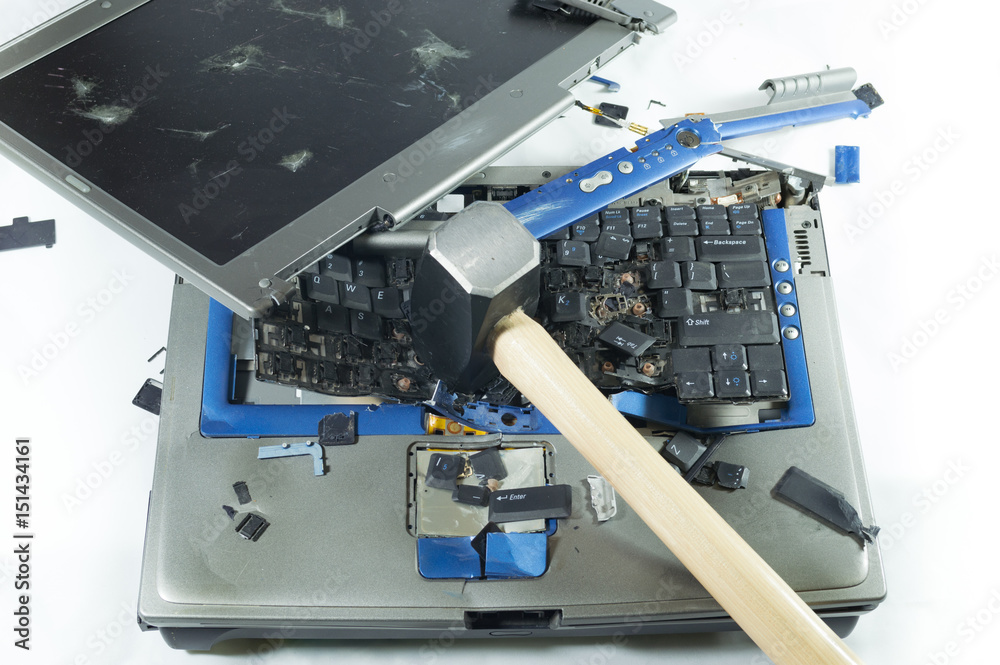 A smashed laptop and screen with a sledgehammer on the keyboard ...