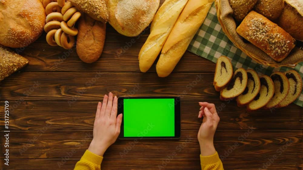 Woman using tablet device with green screen on wooden table with fresh ...