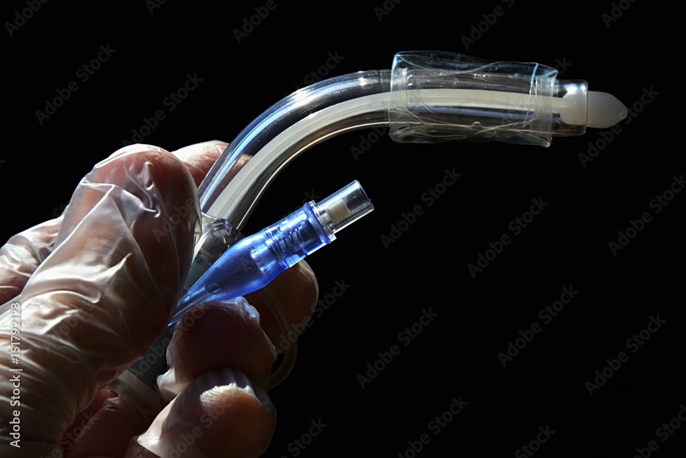 Side view of tracheostomy cannula with deflated cuff and white ...