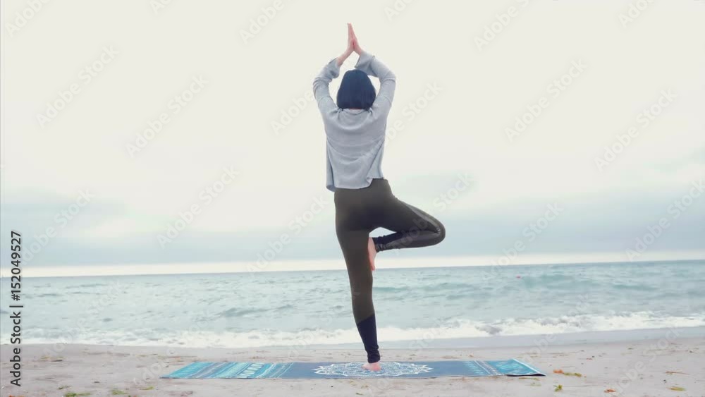 Woman standing a grateful namaste yoga pose on the beach next to the ...