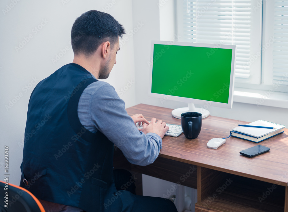 Young man office worker sitting at computer with Chromakey, looking on ...