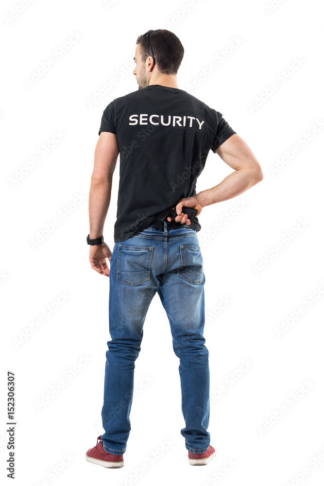 Back view of alerted undercover cop or security agent reaching hand gun ...