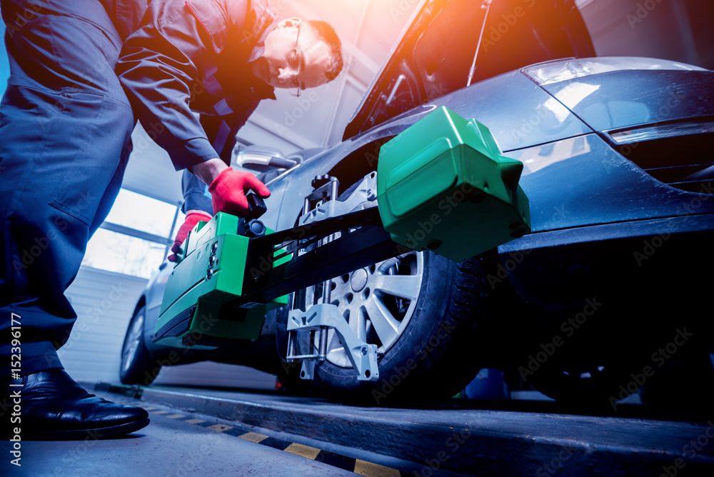 Car mechanic installing sensor during suspension adjustment. Stock ...